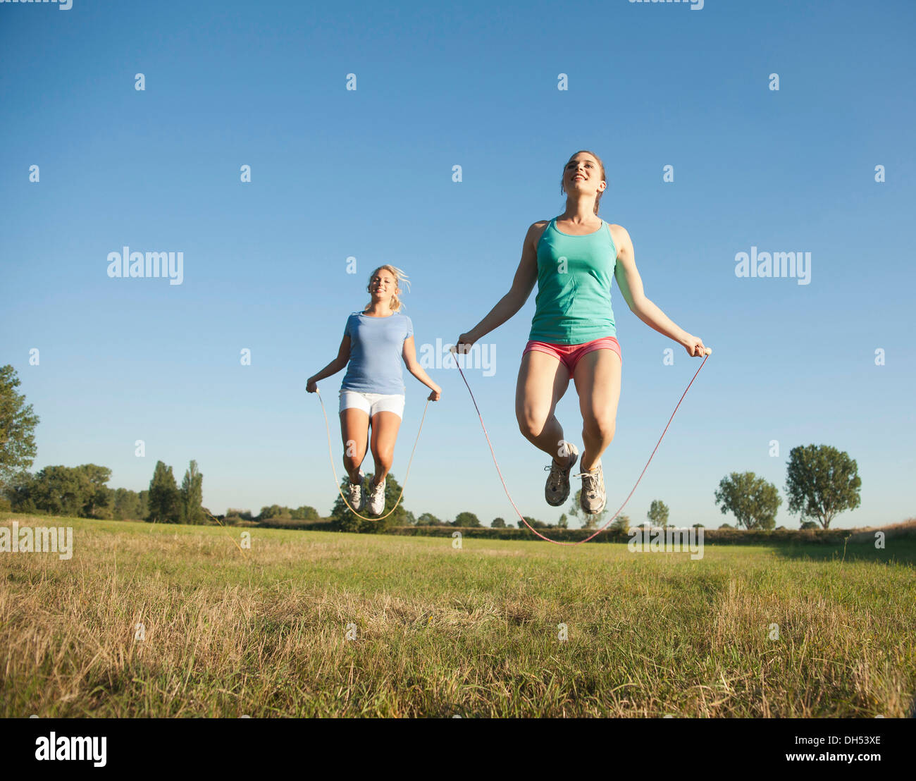 Two young women jumping rope in a meadow Stock Photo - Alamy