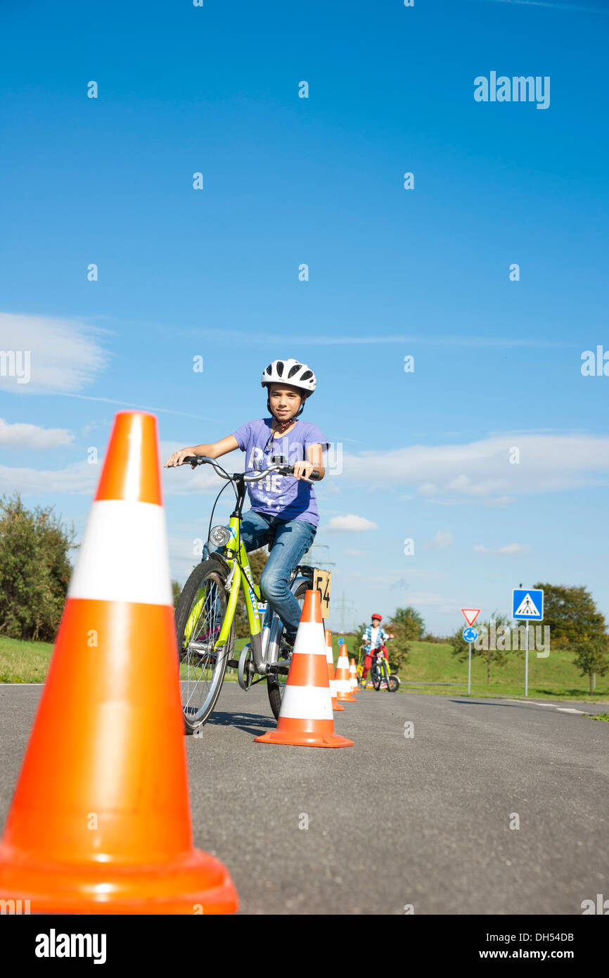 Children practicing to ride slalom on a bicycle at a traffic awareness ...