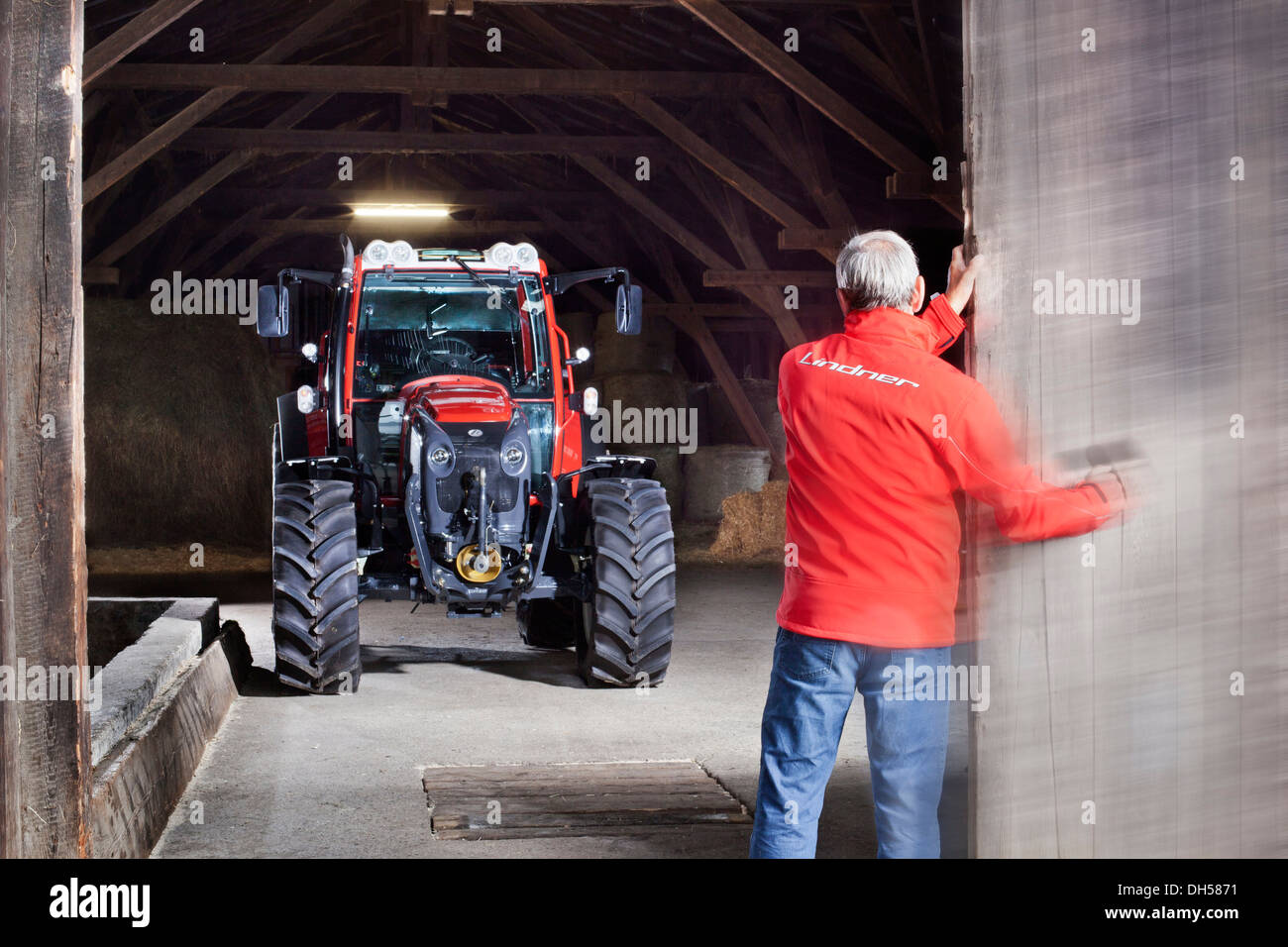 Farmer opening a barn door revealing a tractor behind it, Reith im ...