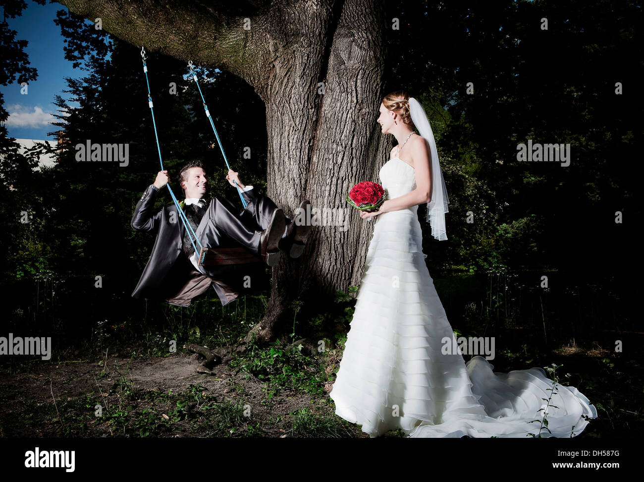 Bride and groom, groom swinging on a swing, bride holding a bridal ...