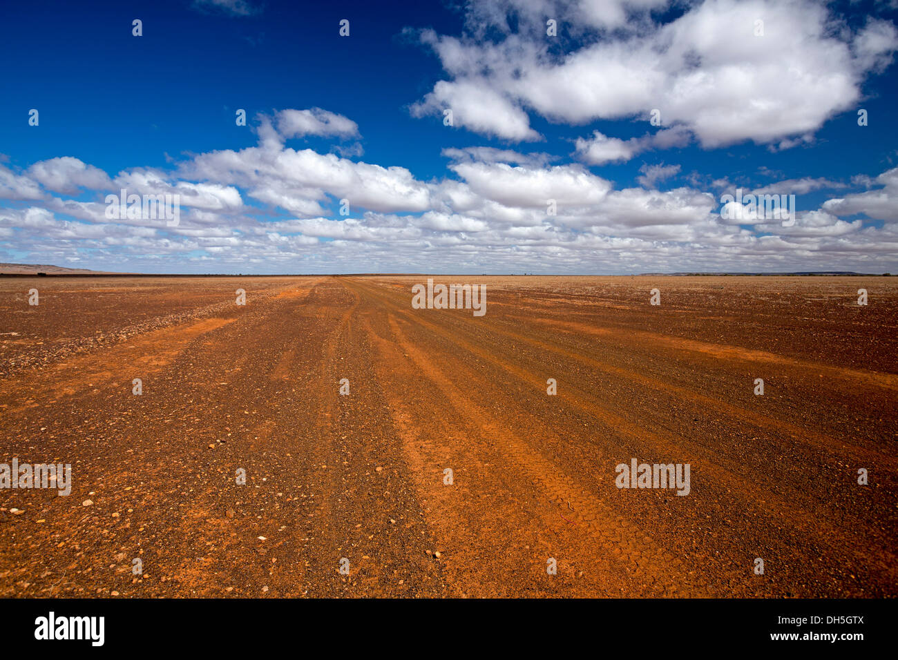 Long red road across vast barren treeless Australian outback plains ...