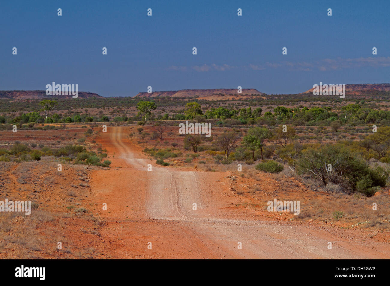 Australian outback landscape with long red dirt road crossing plains to ...