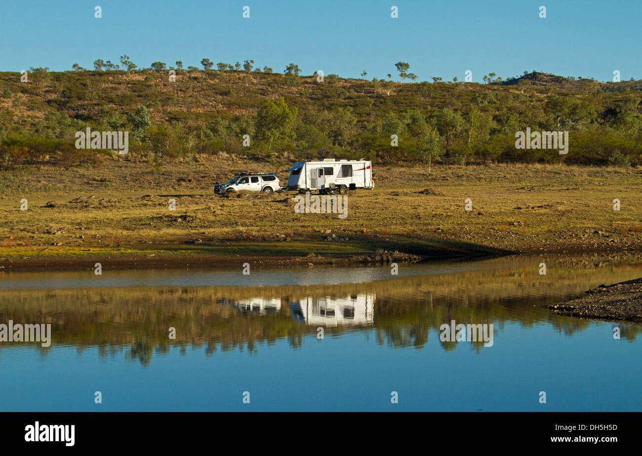 White caravan and car / four wheel drive vehicle parked on grassy hill ...