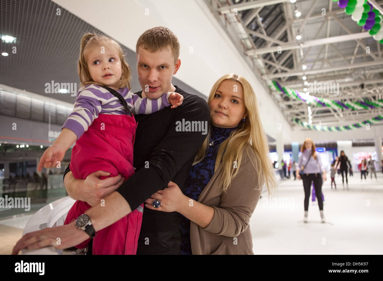 Happy young parents ice skating with their small daughter indoor Stock ...