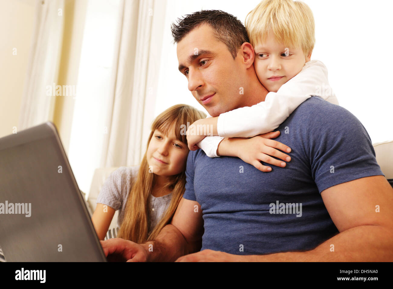 Father with children working on laptop computer at home Stock Photo - Alamy