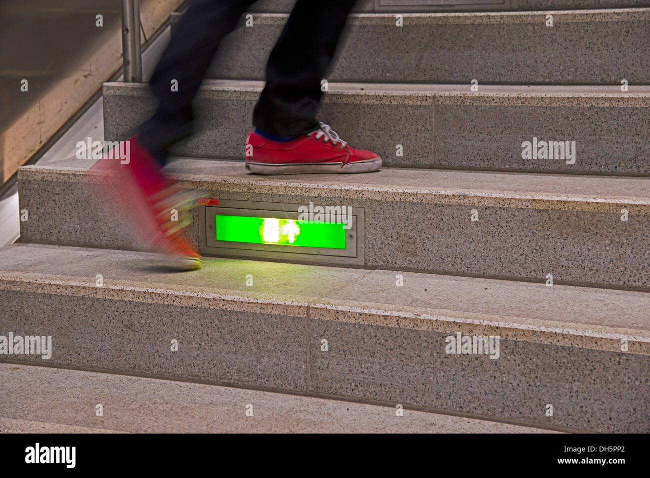 Person rushing up a public staircase with a green illuminated emergency ...