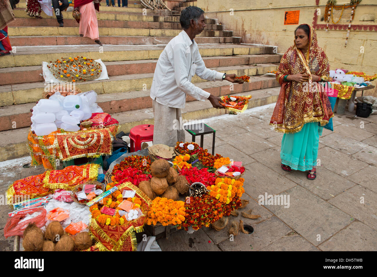 Man at a stall offering small bowls with flowers and ritual offerings ...