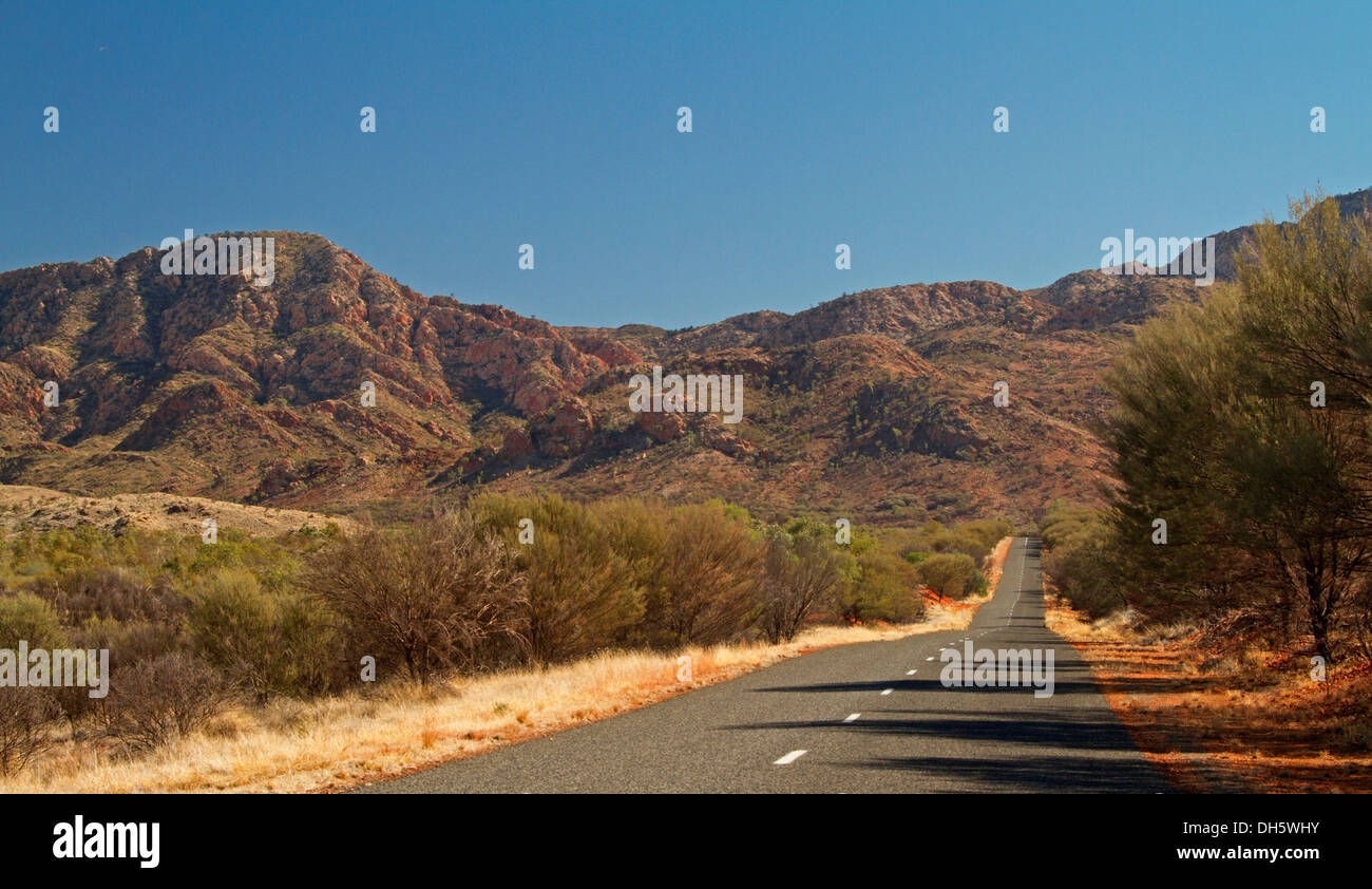 Road in outback Australia bordered by low trees heading towards West ...