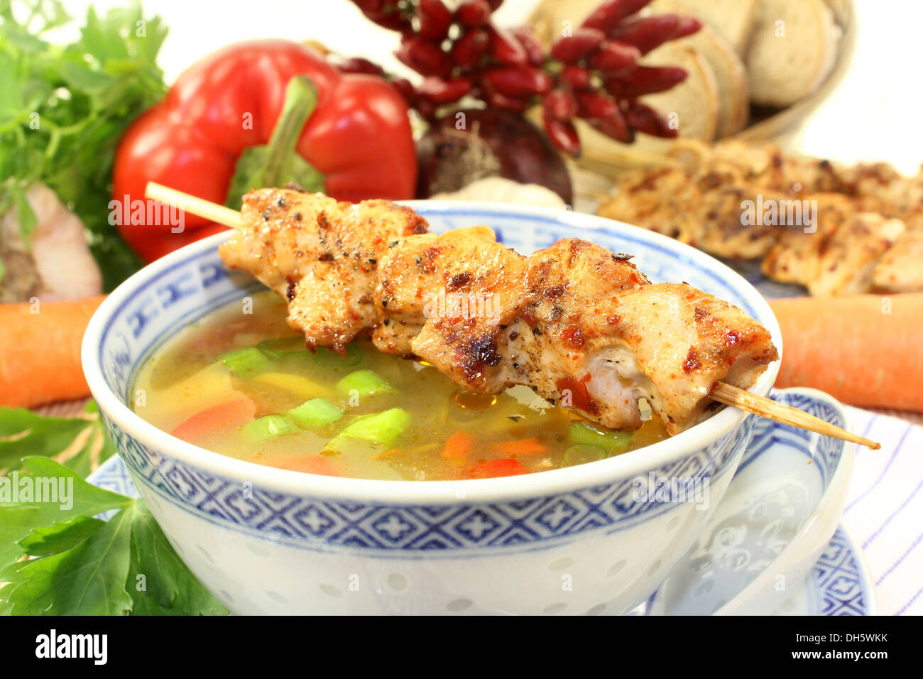 a bowl of chicken consomme and a chicken skewer Stock Photo - Alamy