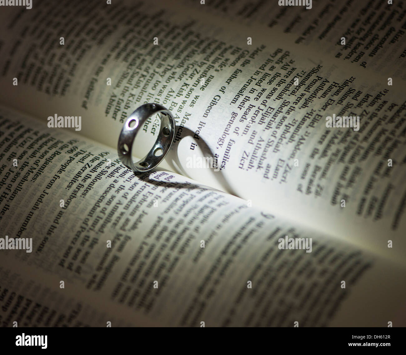 Silver wedding ring giving heart shaped shadow onto bible or holy book ...
