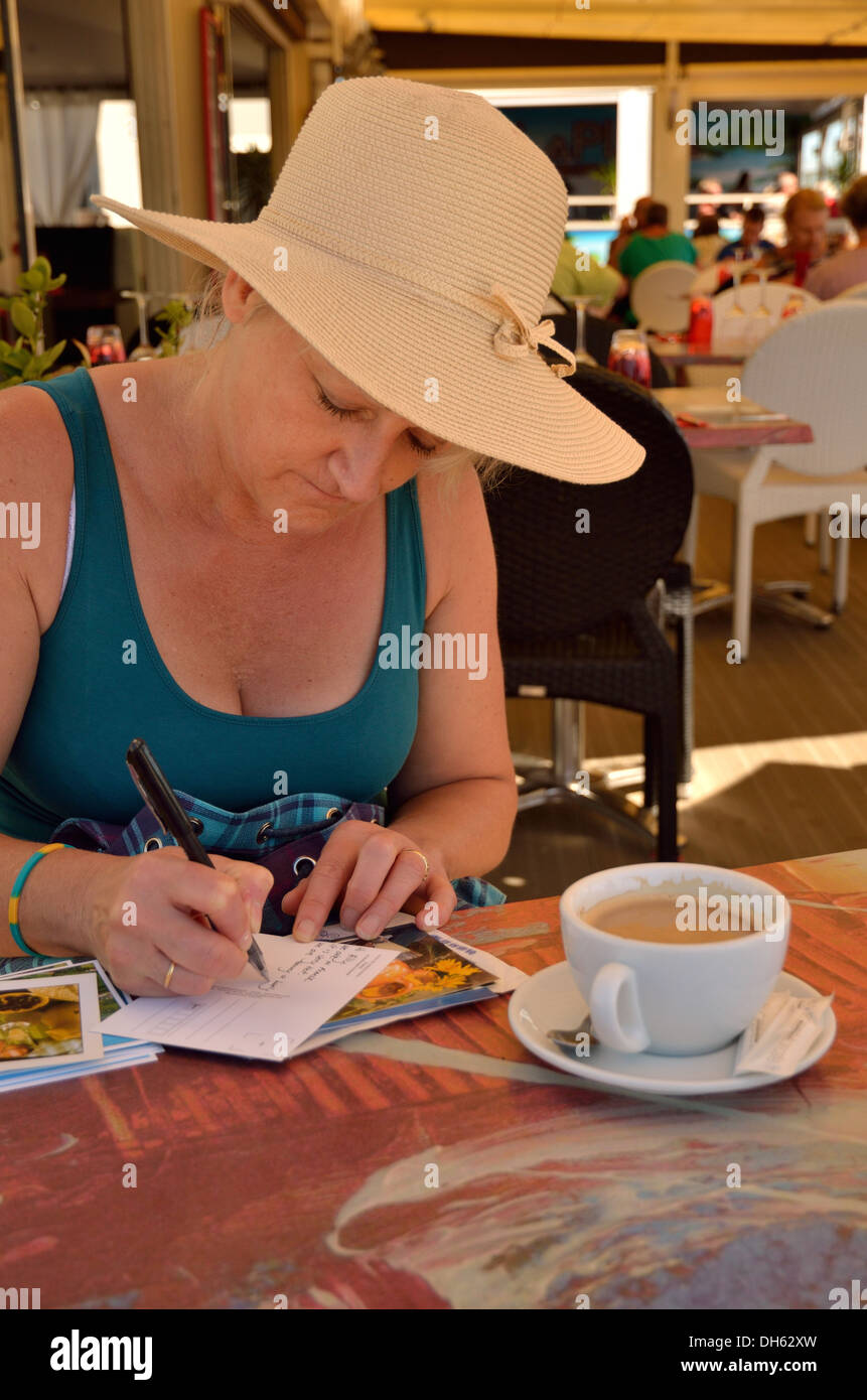 Mature woman on holiday writing postcards in a French cafe Stock Photo ...