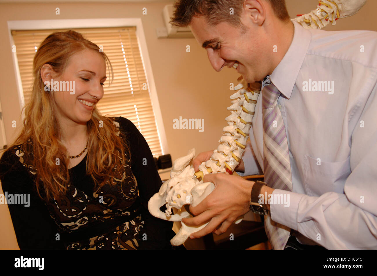 Chiropractor and patient. The chiropractor is using a model of a human ...