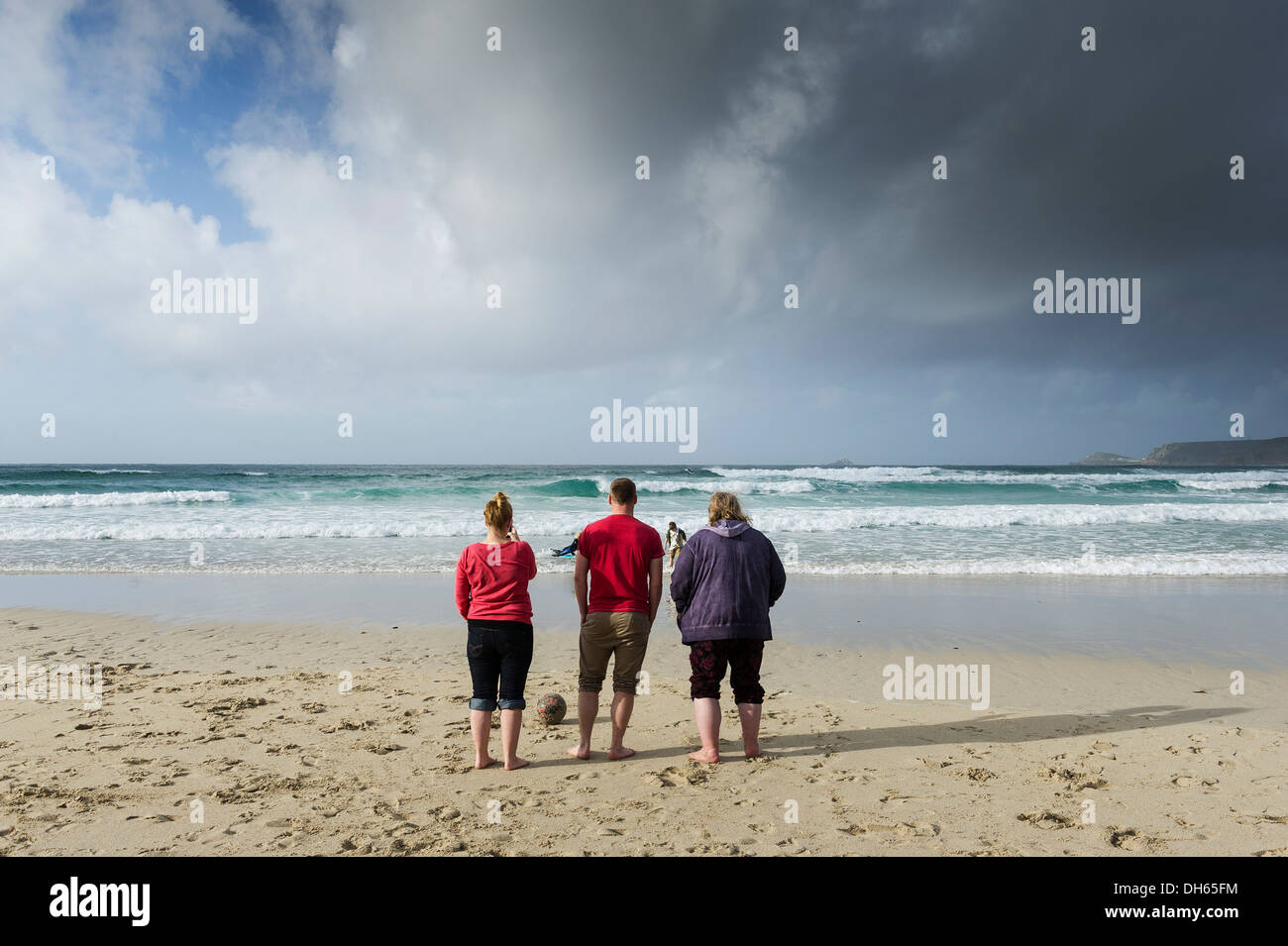Three people standing on the beach at Sennen Cove Stock Photo - Alamy