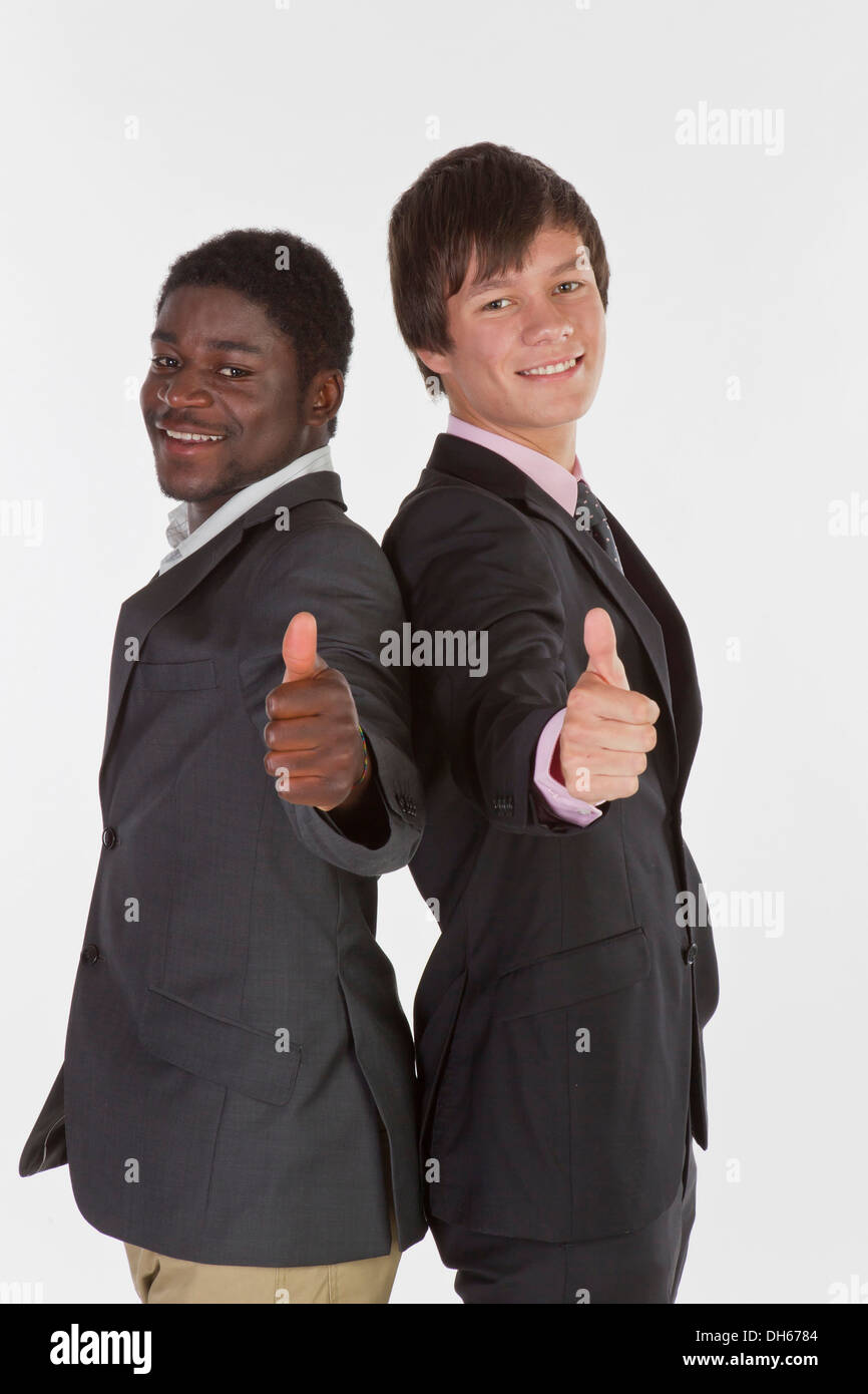 Two young businessmen standing back to back and making a thumbs-up ...