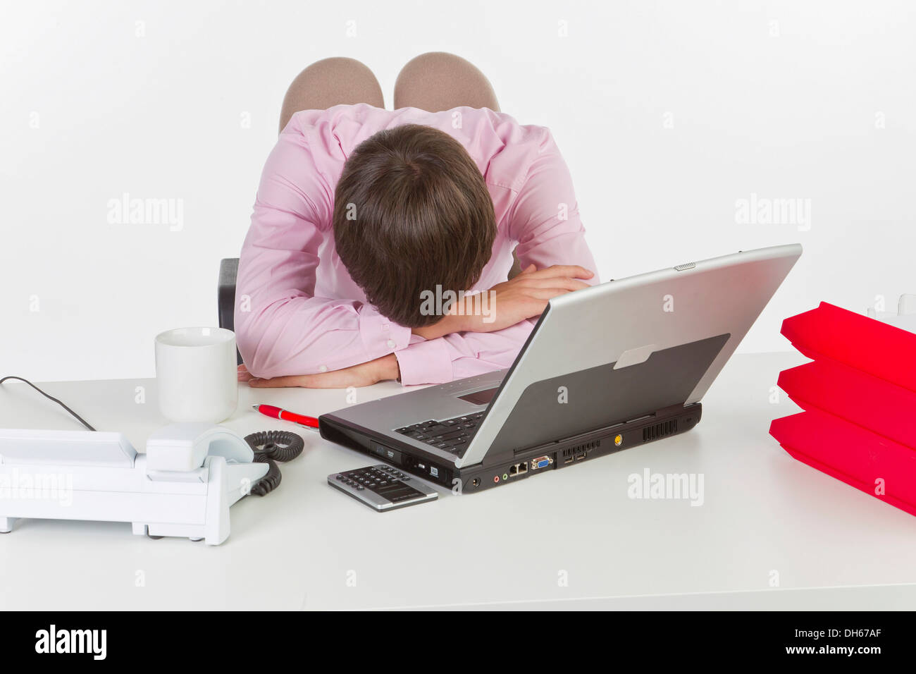 Young man at his desk in the office with a laptop computer, head ...