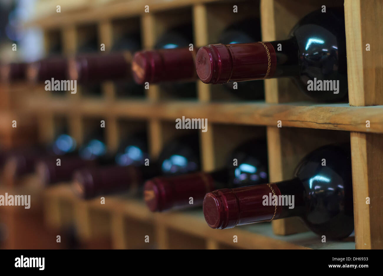 Red wine bottles stacked on wooden racks Stock Photo - Alamy
