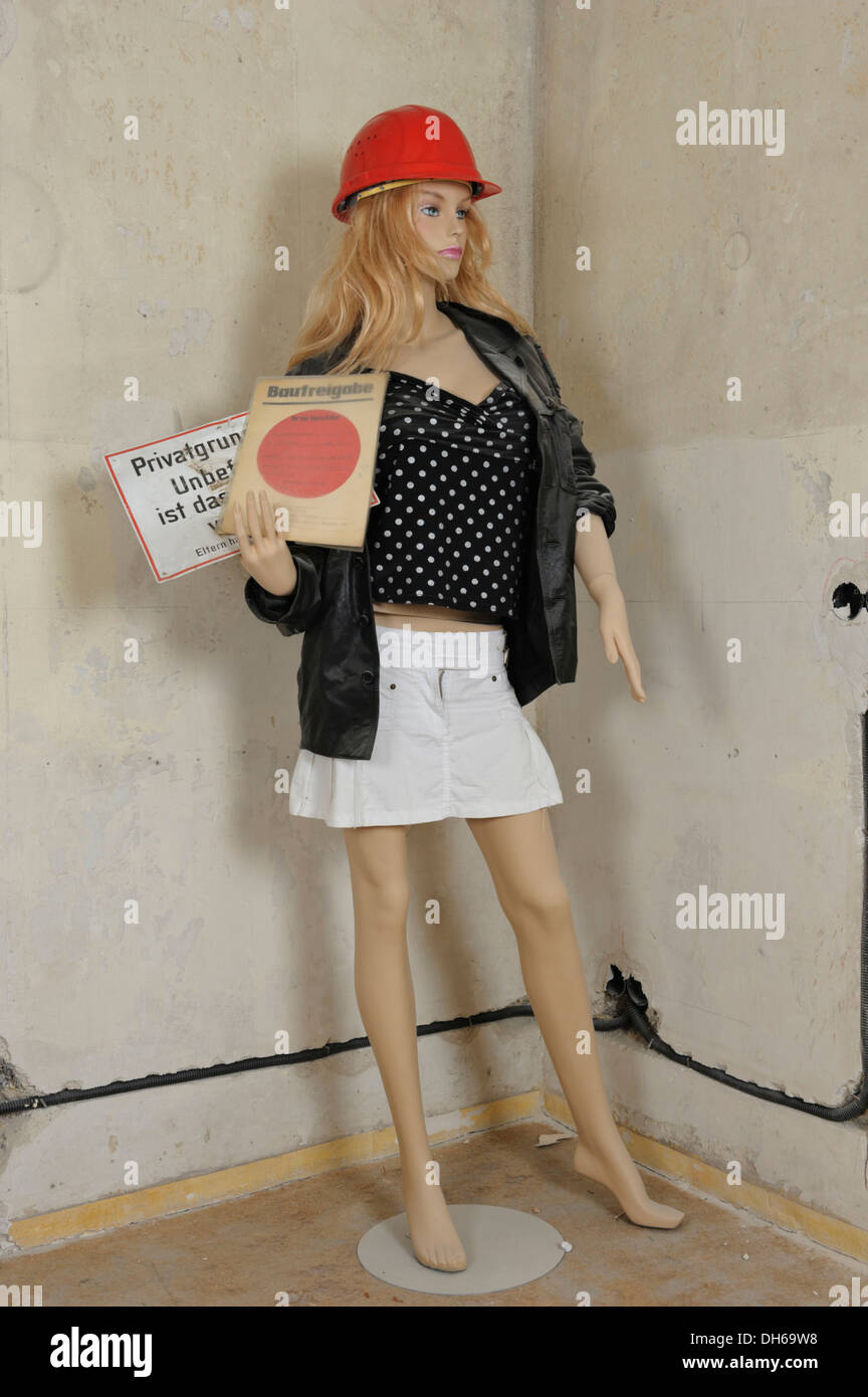 Mannequin with a hard hat on a building site, holding a construction ...