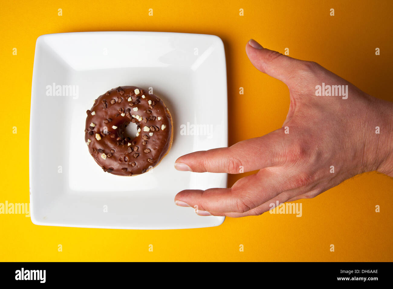 Frosted glazed Donut with chocolate sprinkles being grab at Stock Photo ...