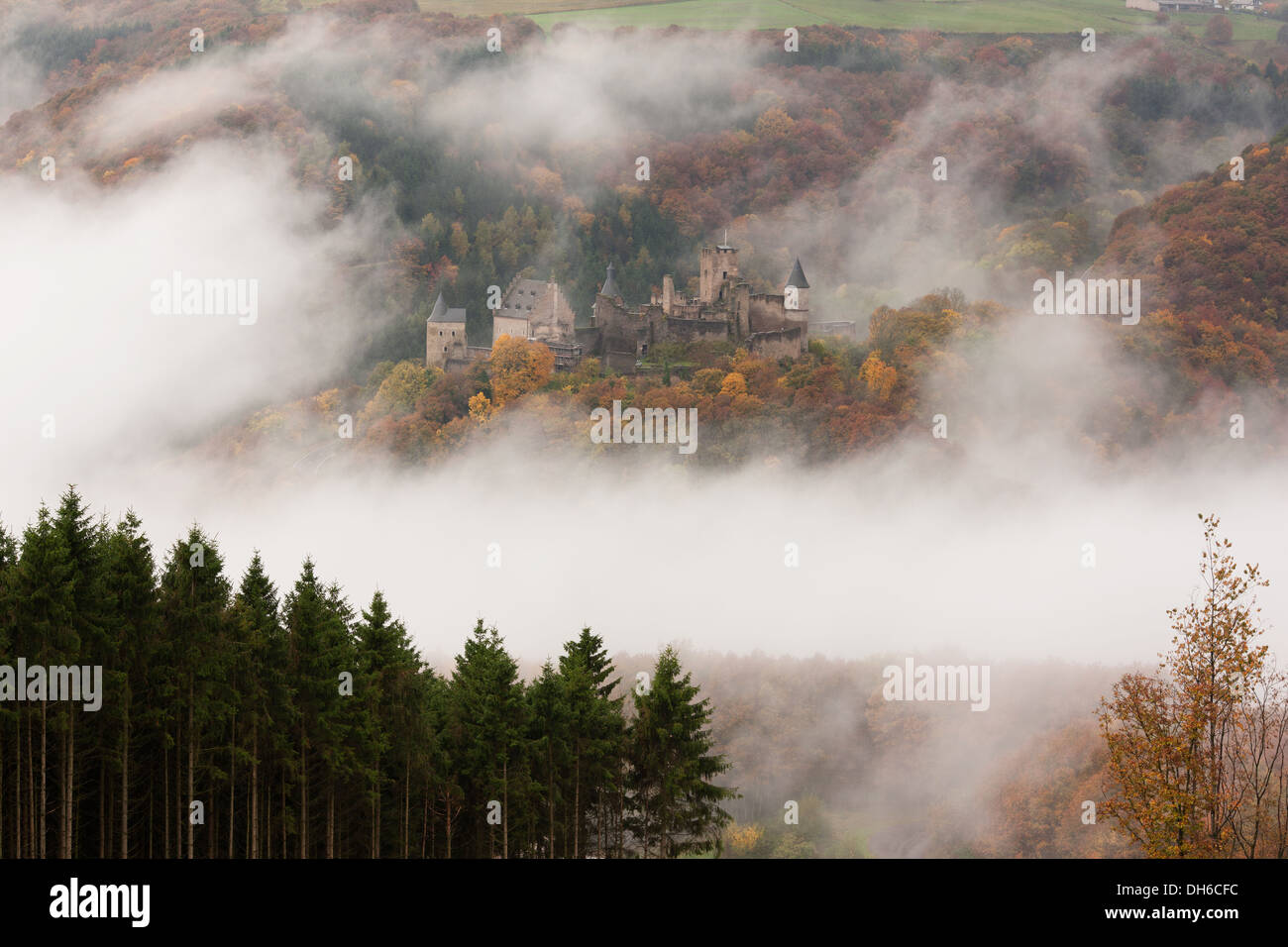 Medieval castle shrouded in fog seen from the other side of the valley ...