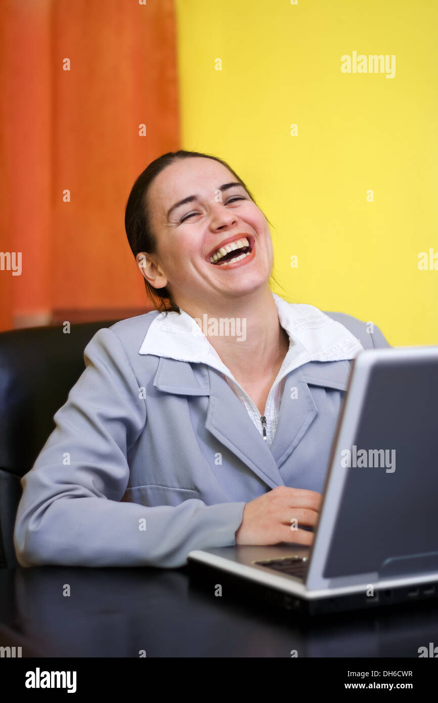 Laughing business woman behind laptop Stock Photo - Alamy