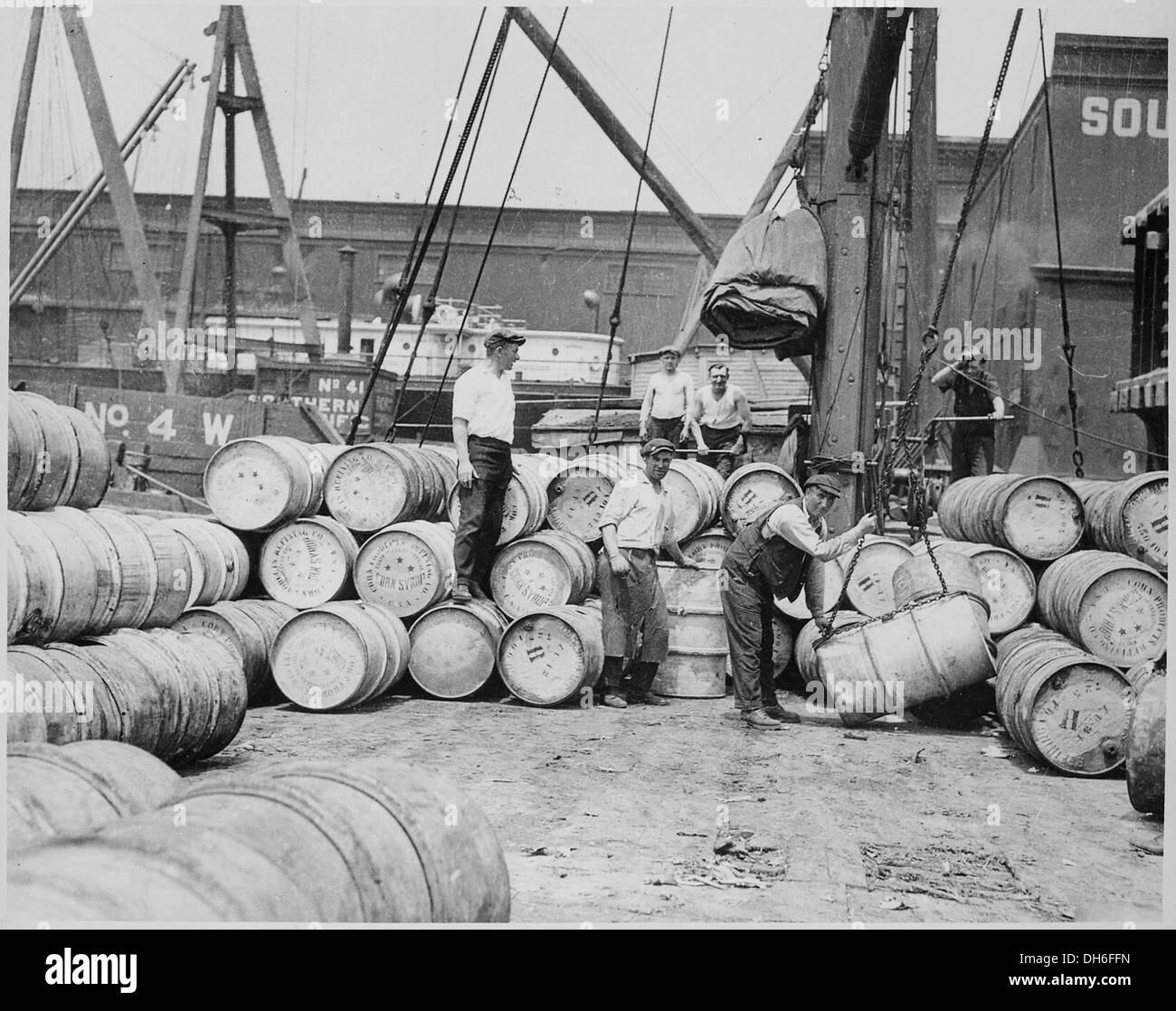 This photograph shows stevedores loading barrels of corn syrup onto a ...