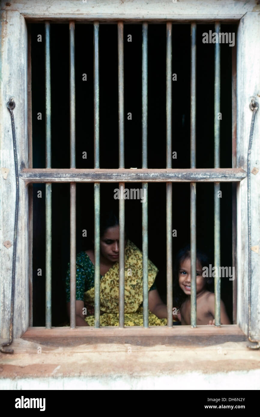 two people looking out through barred window india Stock Photo - Alamy