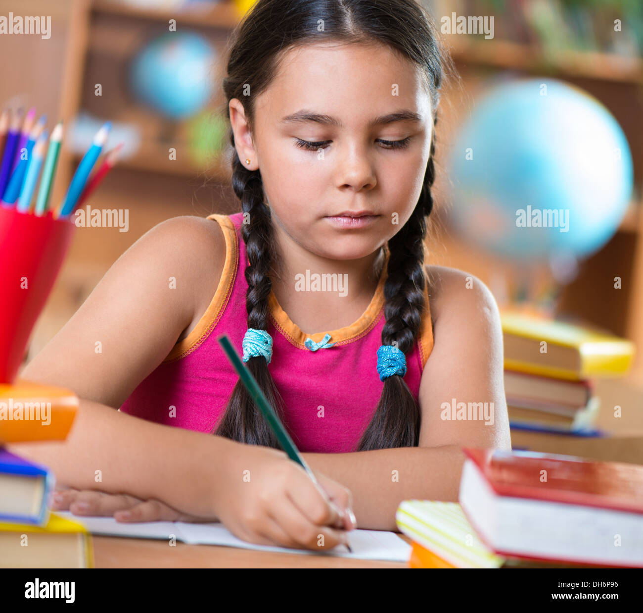 Cute hispanic girl writing in notebook in classroom at school Stock ...