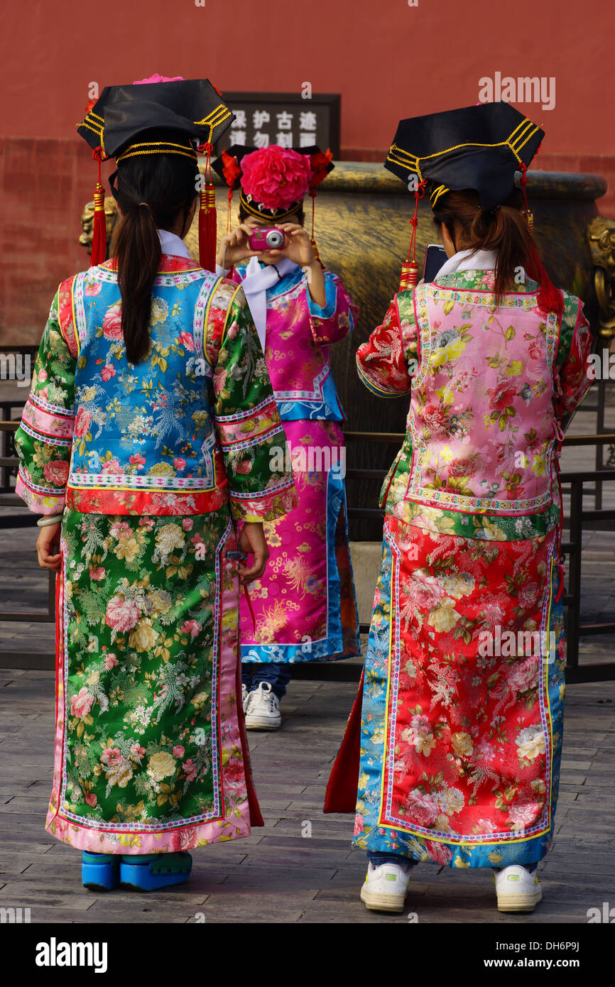 Chinese girls on a day out in the Forbidden City, Beijing, try on ...
