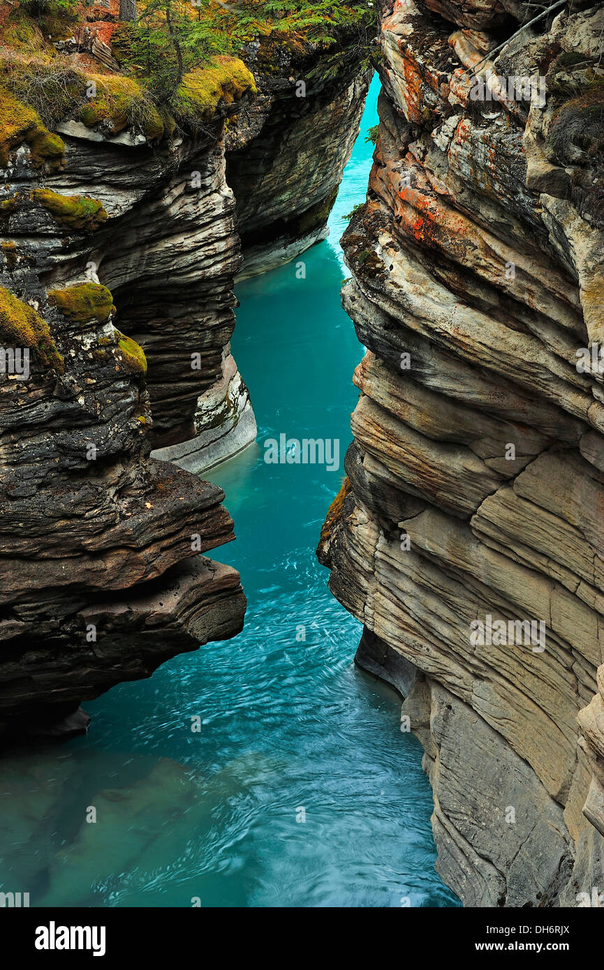 A narrow gorge cut through the rocks with the blue water of the ...