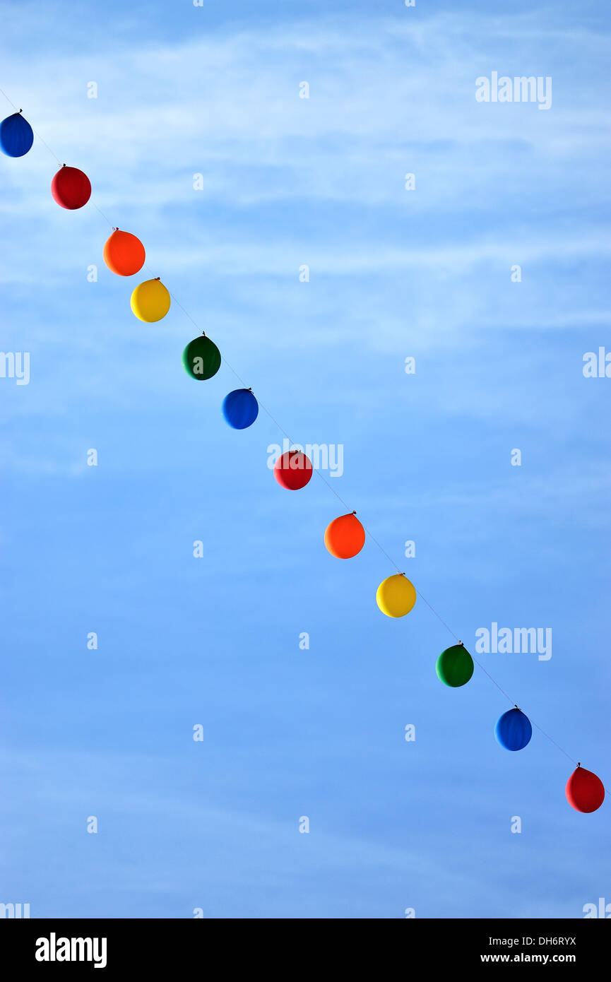 A string of colorful balloons floating high in the sky Stock Photo - Alamy
