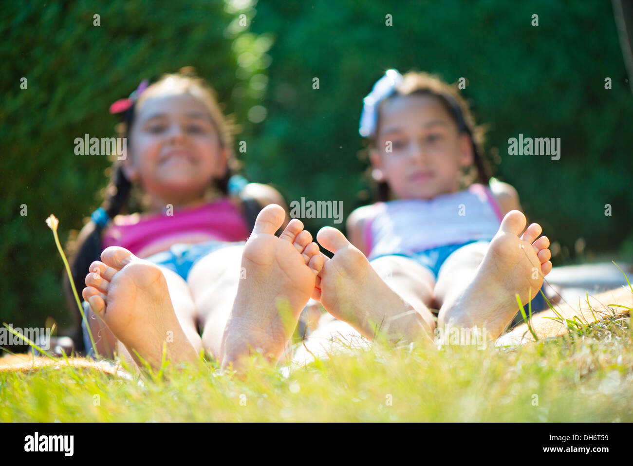 Two happy sisters lying on green grass outdoors in summer park Stock ... Two happy sisters lying on green grass outdoors in summer park Stock ...