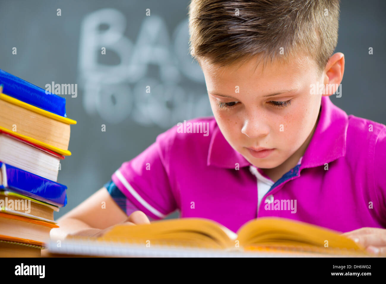 Cute schoolboy reading in classroom foreground blackboard Stock Photo ...