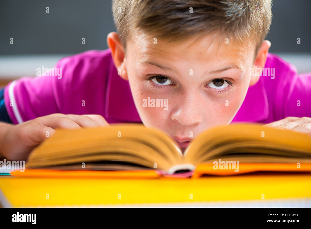 Cute schoolboy reading in classroom foreground blackboard Stock Photo ...