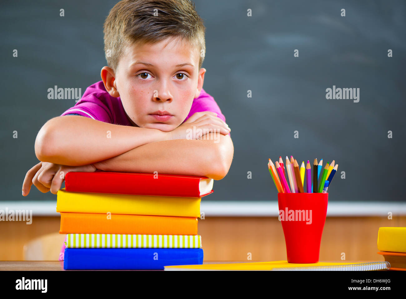 Adorable schoolboy with stack of books in classroom Stock Photo - Alamy