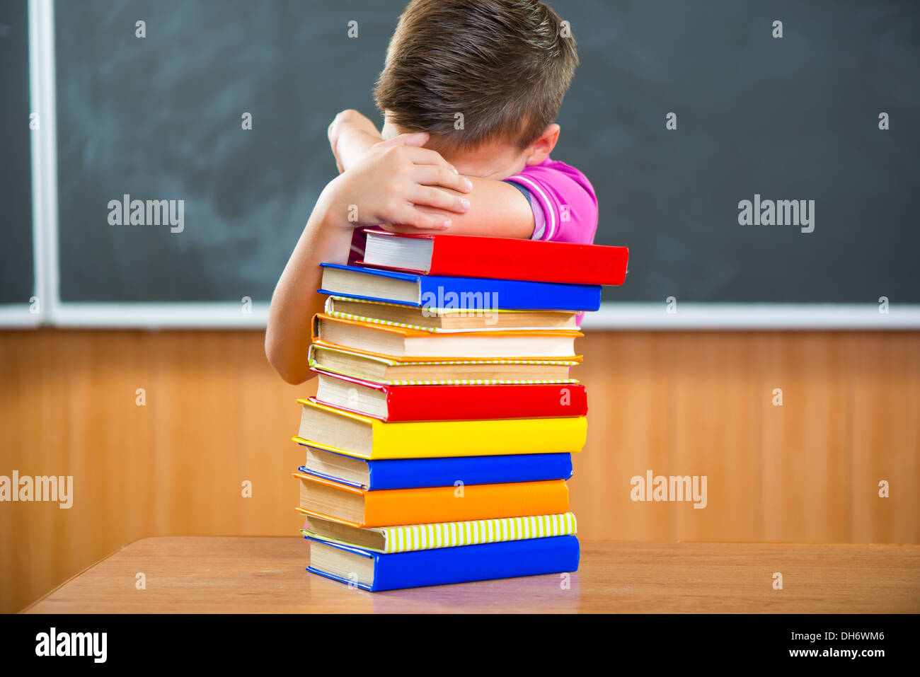 Adorable schoolboy with stack of books in classroom Stock Photo - Alamy