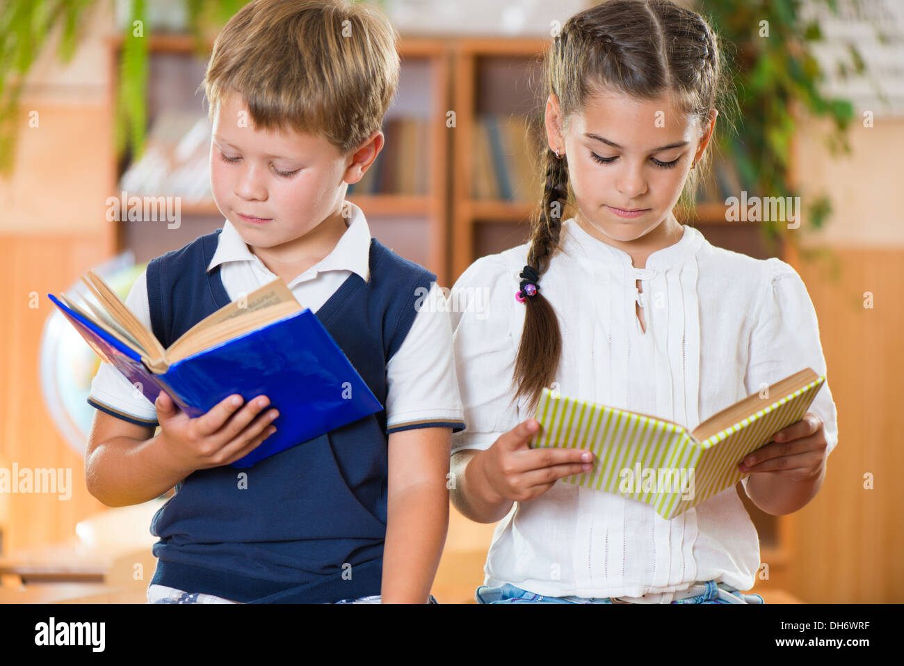Portrait of two diligent pupil with books in library Stock Photo - Alamy