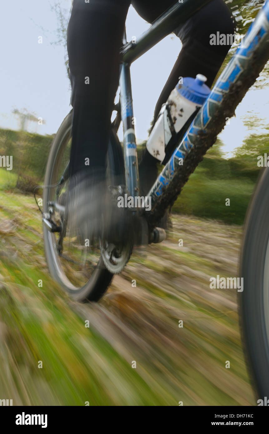 Mountain biking at speed along a muddy cross country route showing ...