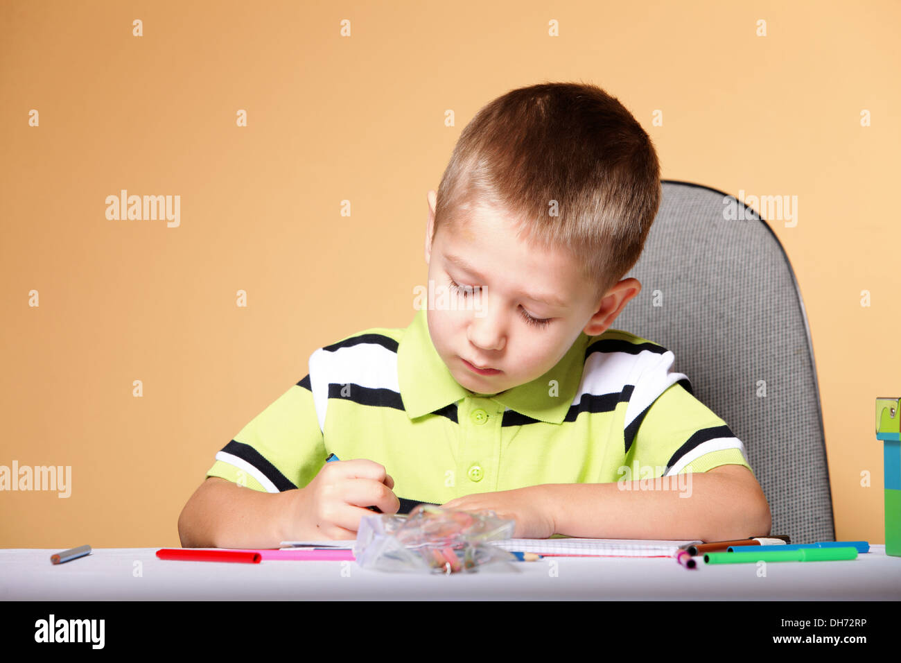 little boy drawing with color pencils on orange background Stock Photo ...