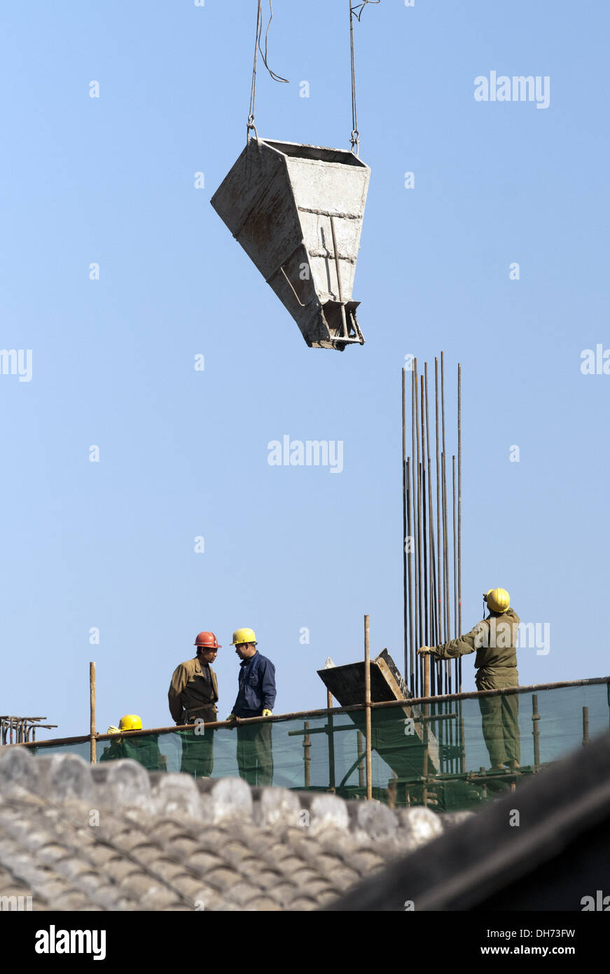 Builders using a crane to load cement on a construction site in Beijing ...