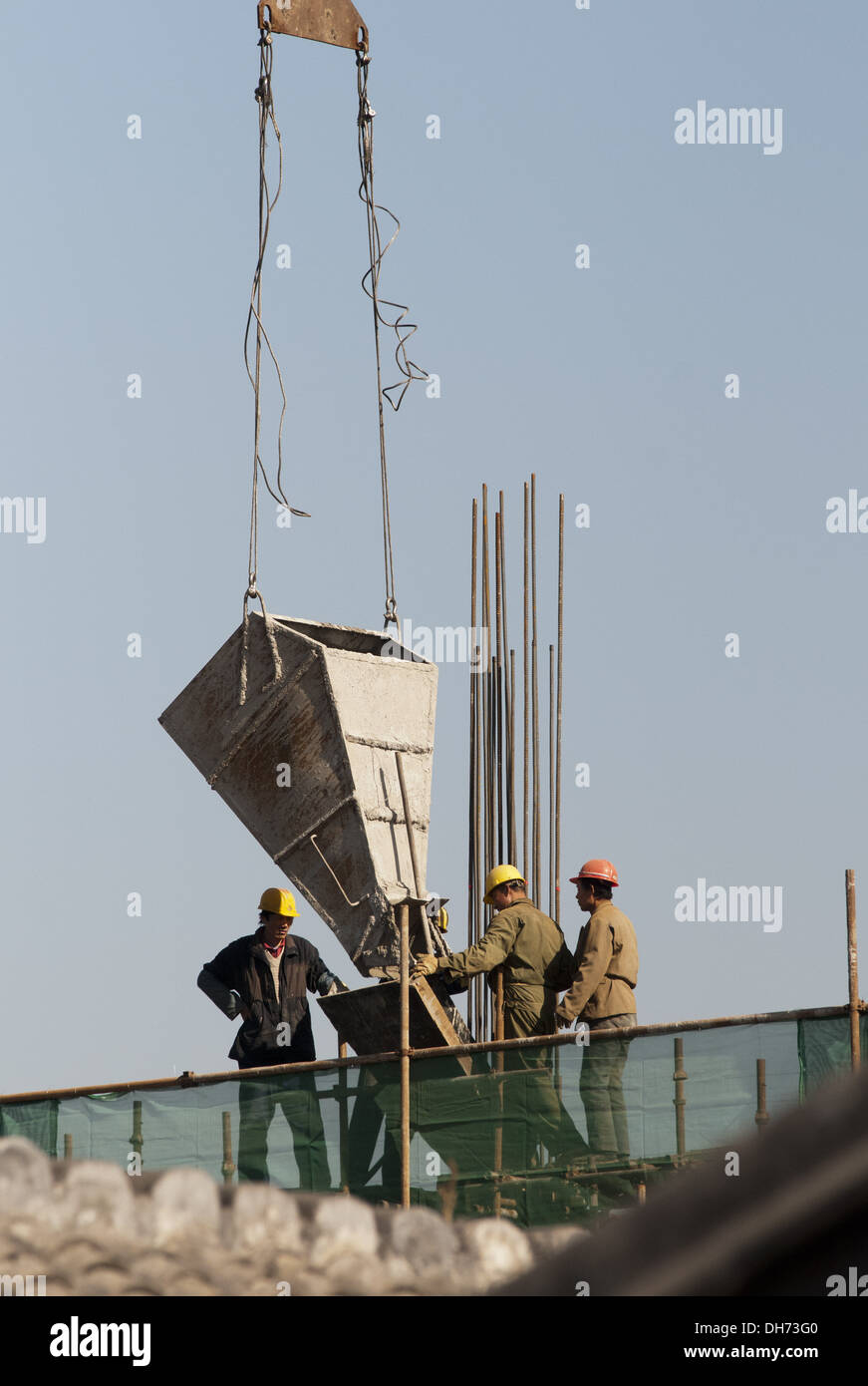 Builders using a crane to load cement on a construction site in Beijing ...
