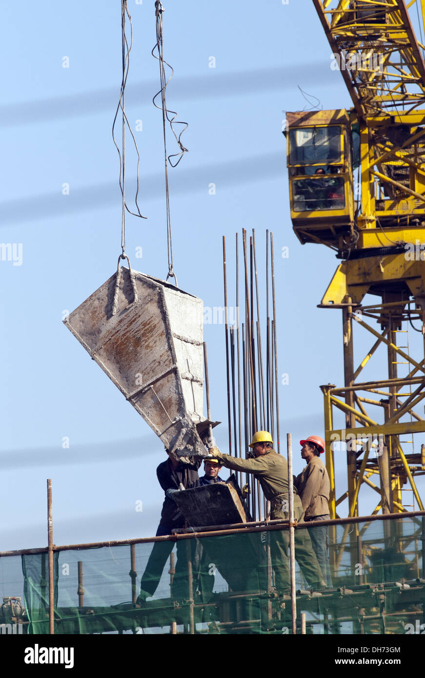 Builders using a crane to load cement on a construction site in Beijing ...