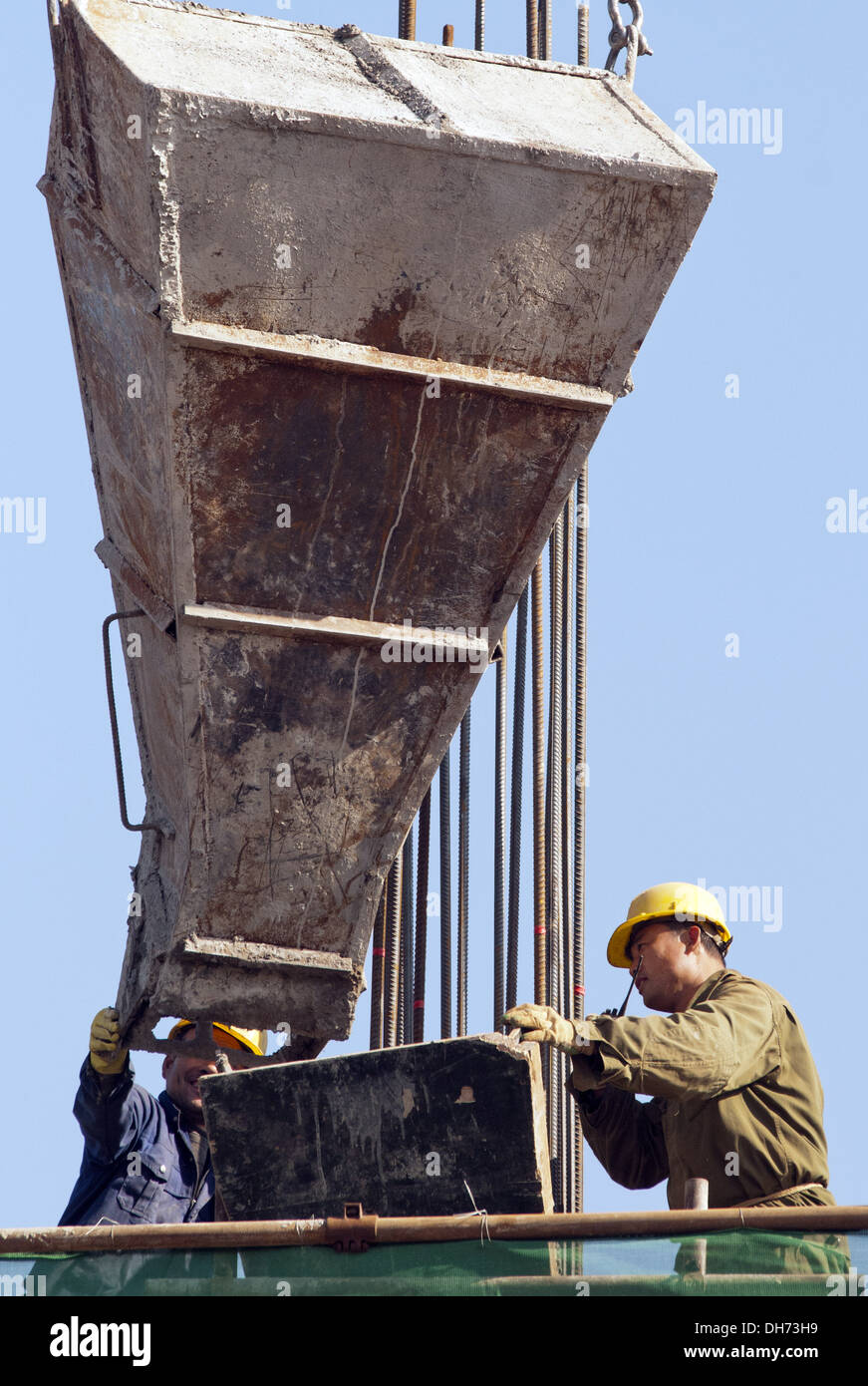 Builders using a crane to load cement on a construction site in Beijing ...