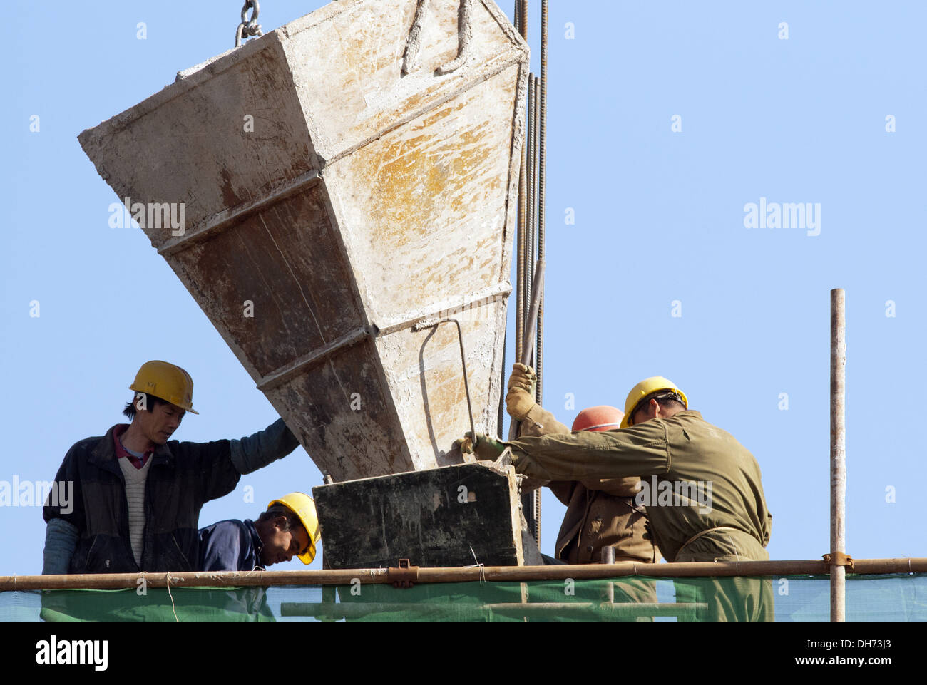 Builders using a crane to load cement on a construction site in Beijing ...