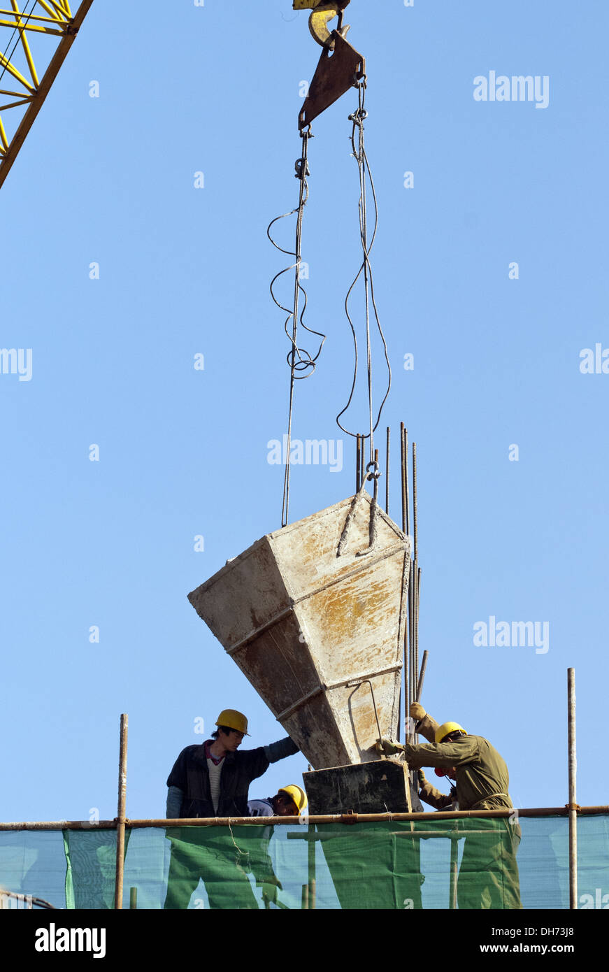 Builders using a crane to load cement on a construction site in Beijing ...