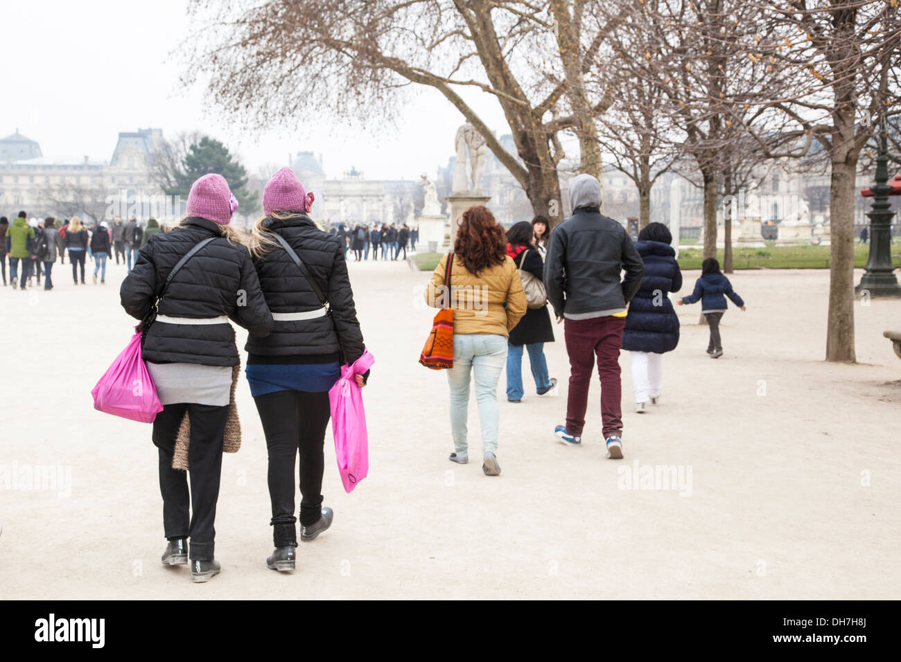 twin sisters walk arm in arm, dressed in the same clothes, down the ...