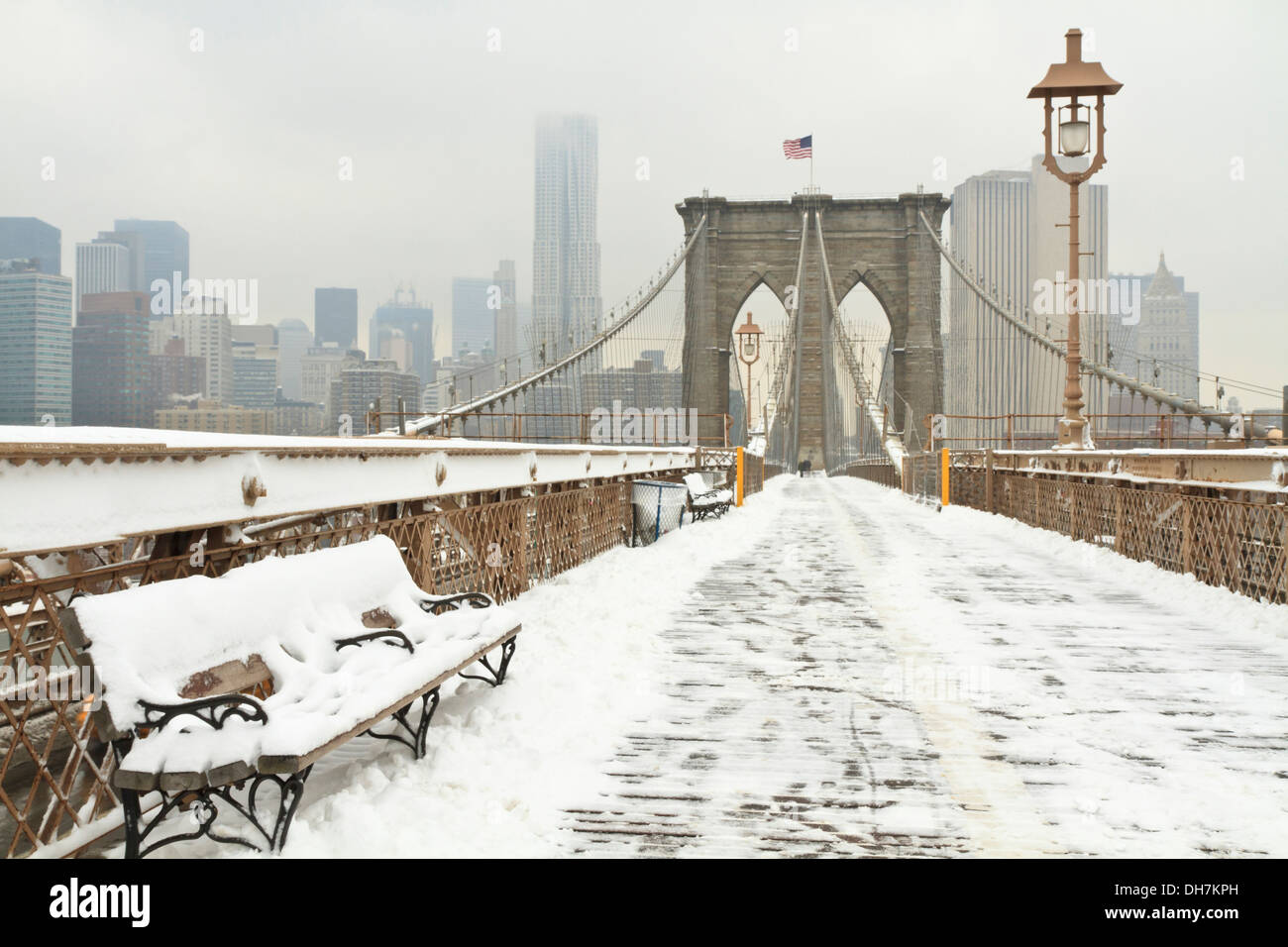 Horizontal photo of a bench covered in snow on an almost empty Brooklyn ...