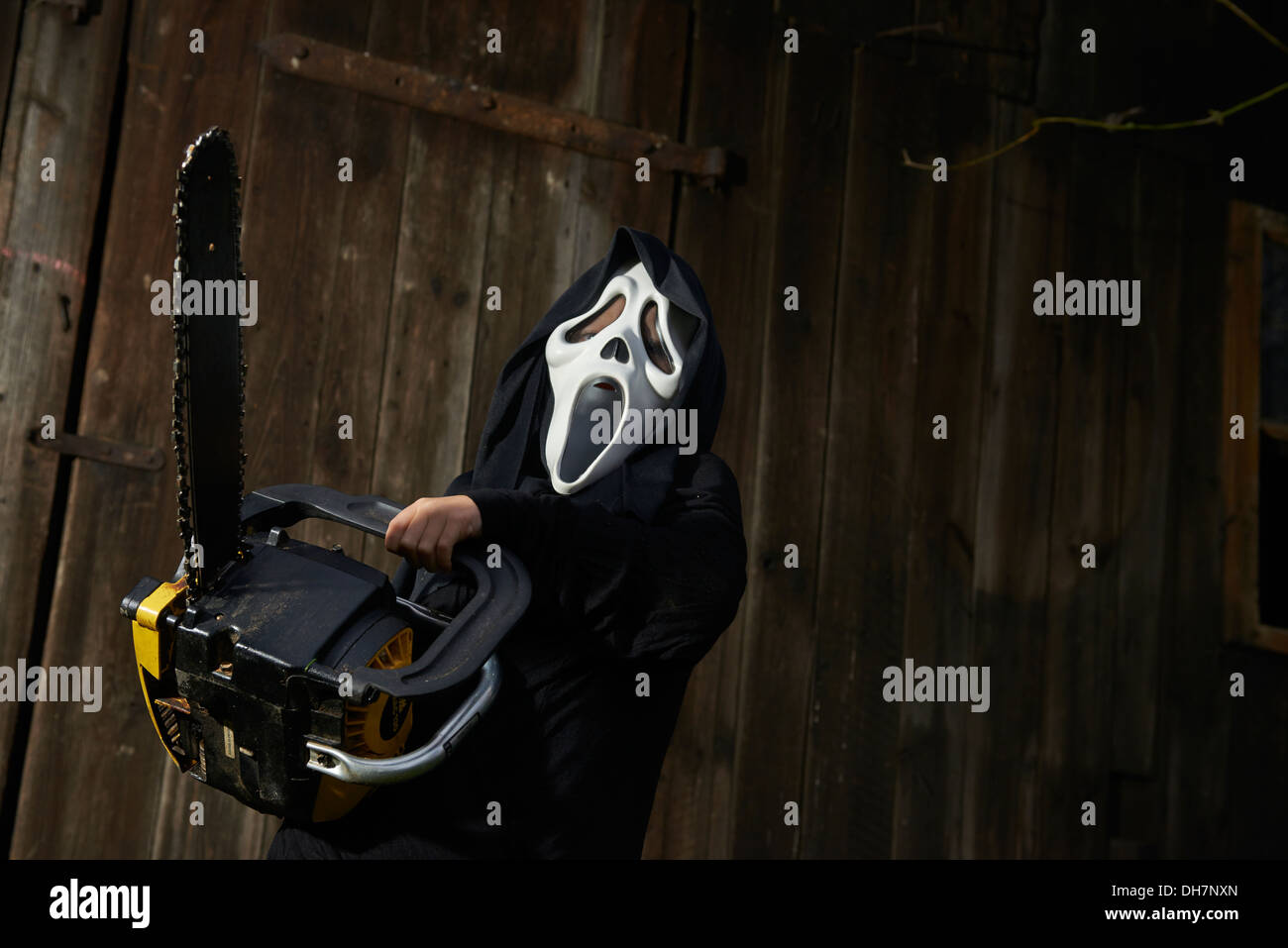 Man in scary "scream" mask holds chainsaw. Mask of grim reaper ...