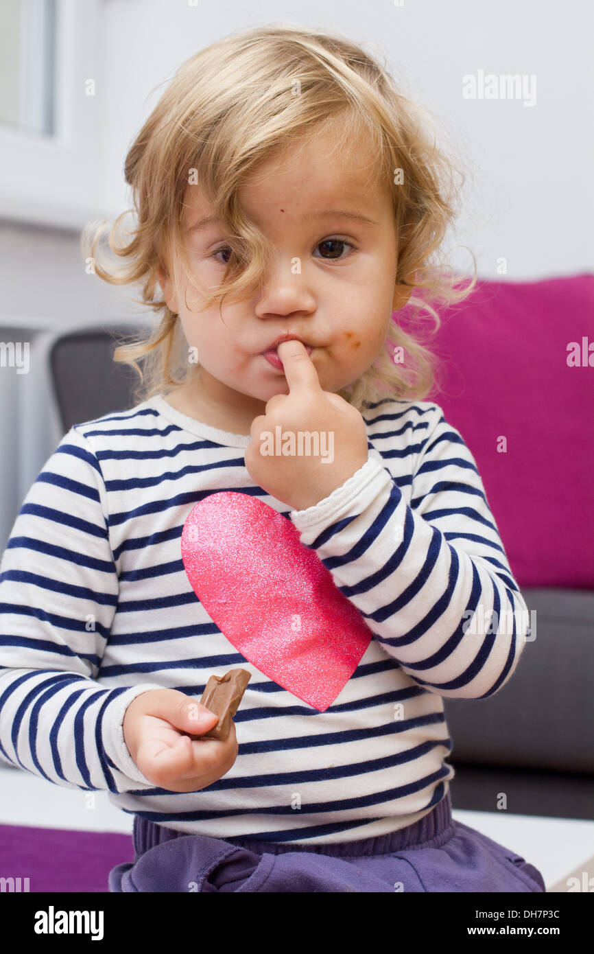 Portrait of cute little girl eating sweets Stock Photo - Alamy