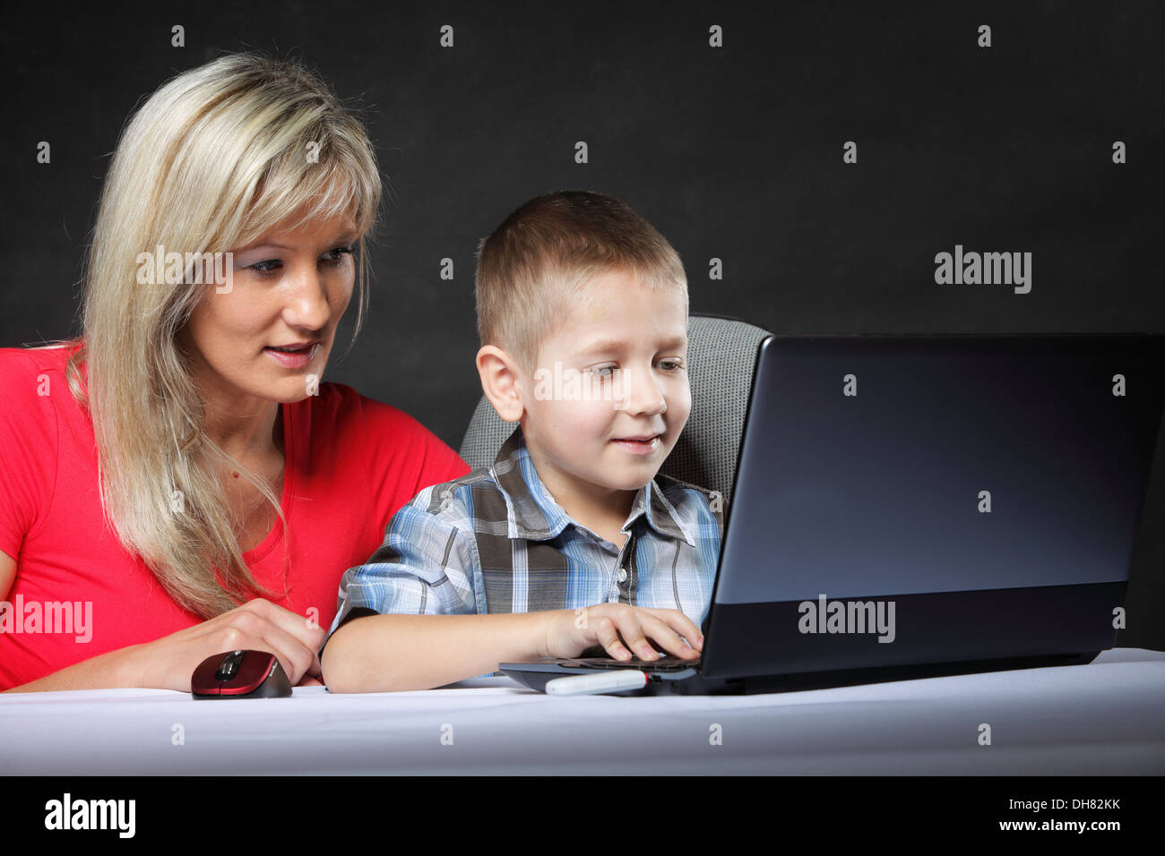 mother with son together looking on the laptop computer black ...