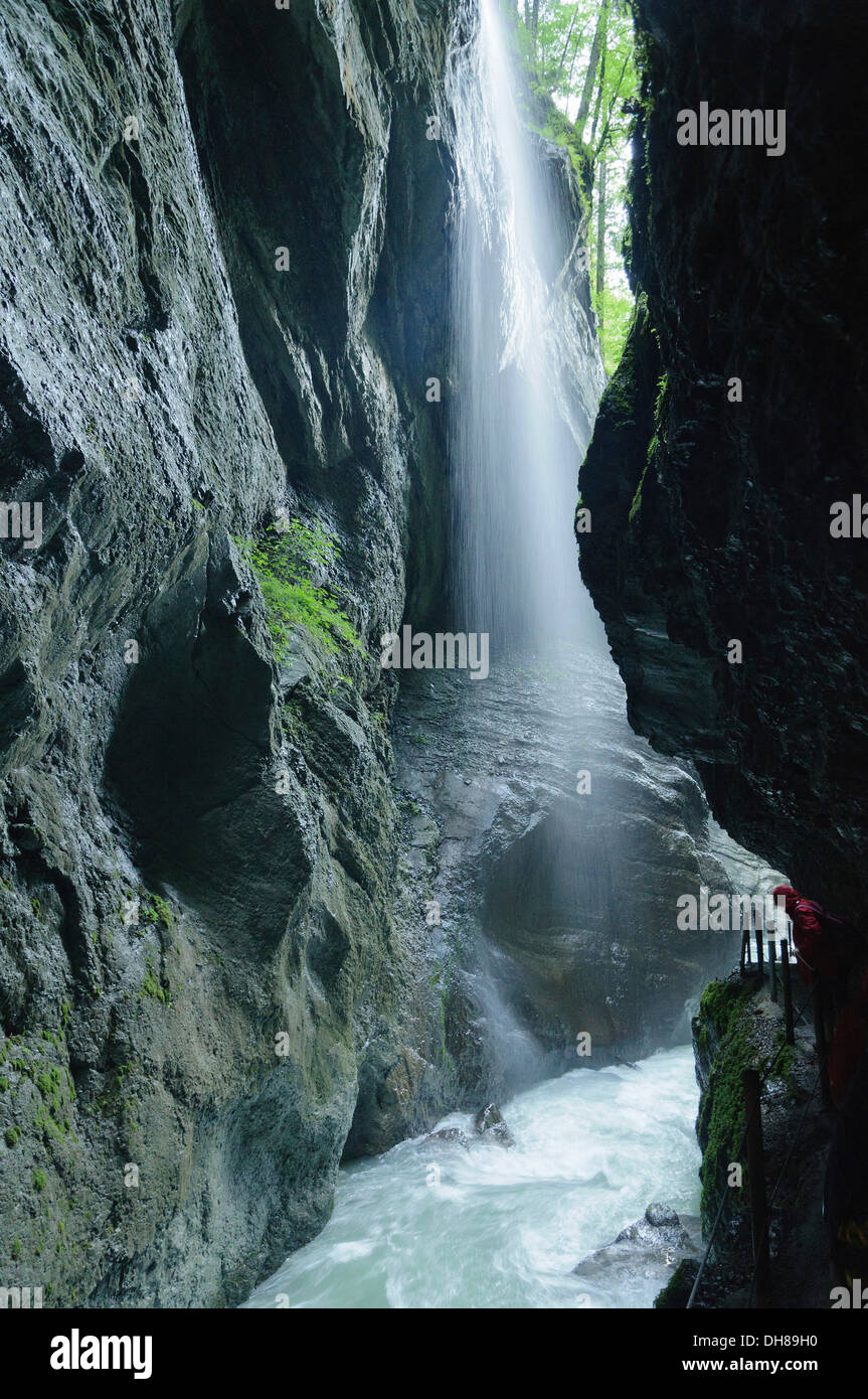 Hiker observing a waterfall in the Partnachklamm gorge, Reintal, Upper ...